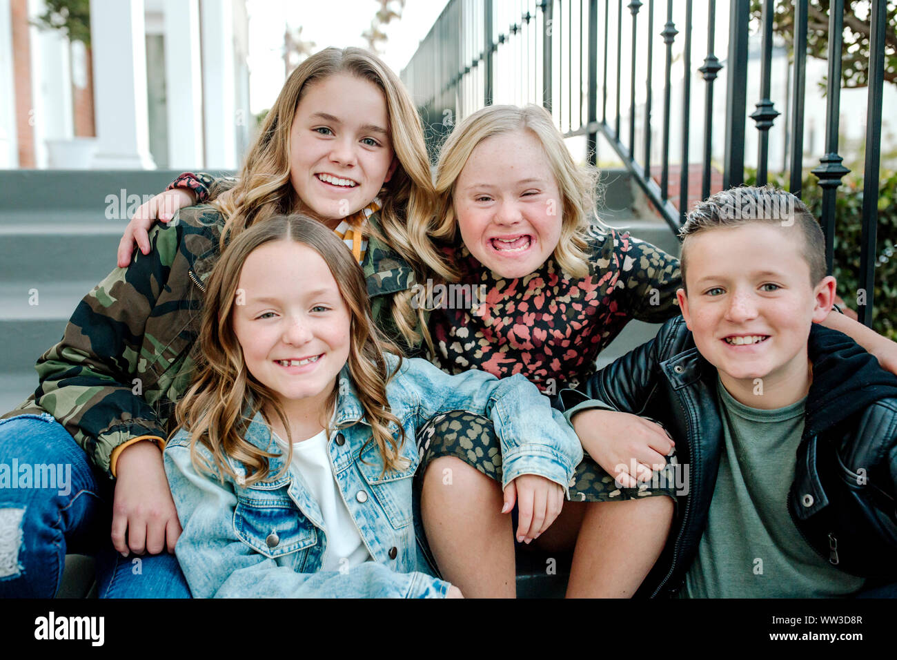 Smiling siblings on steps with iron railing Stock Photo - Alamy