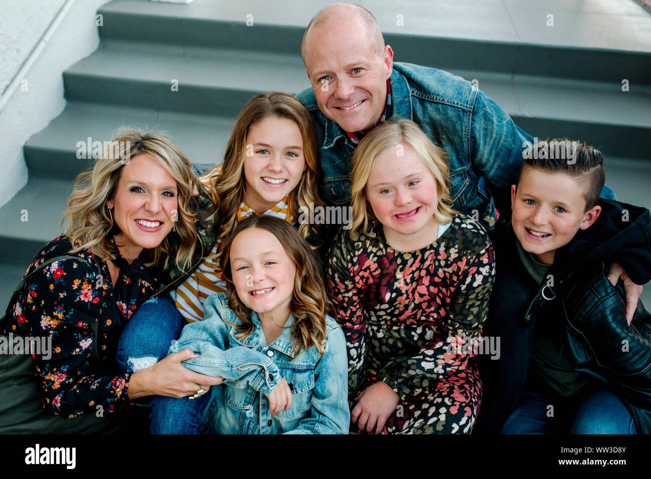 Diverse smiling family huddled on steps Stock Photo - Alamy