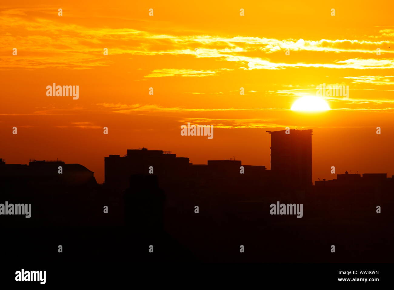 The sun rising behind a building in Leeds City Centre Stock Photo - Alamy