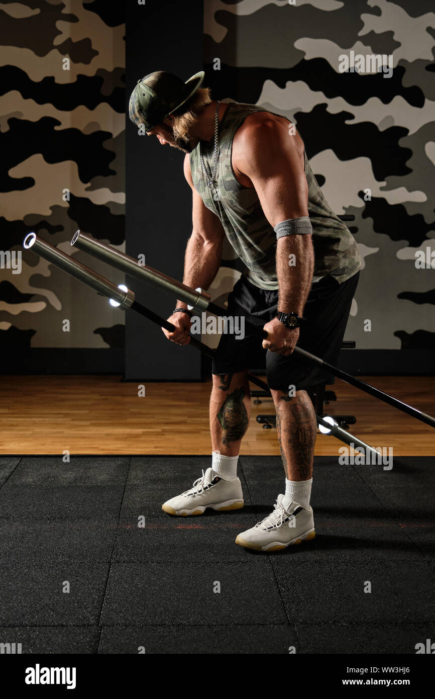 Muscular man in a sports uniform and a baseball cap is bending over ...