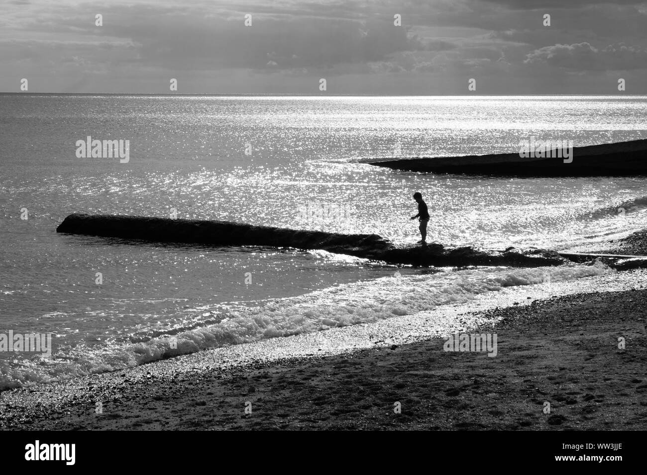 A six year old unrecognisable boy in the distance walking along a jetty ...