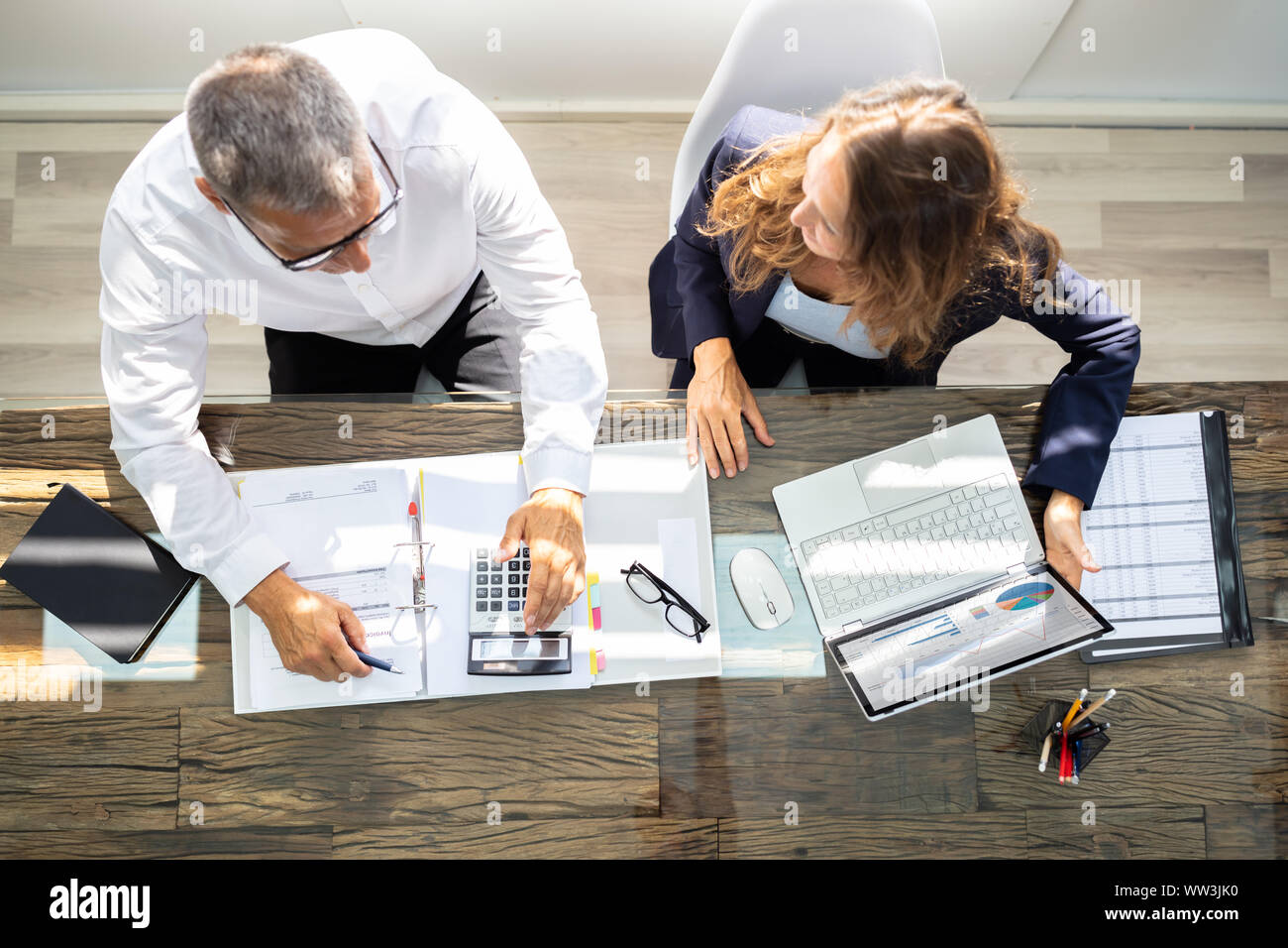 An Overhead View Of Two Businesspeople Calculating Invoice In Office ...