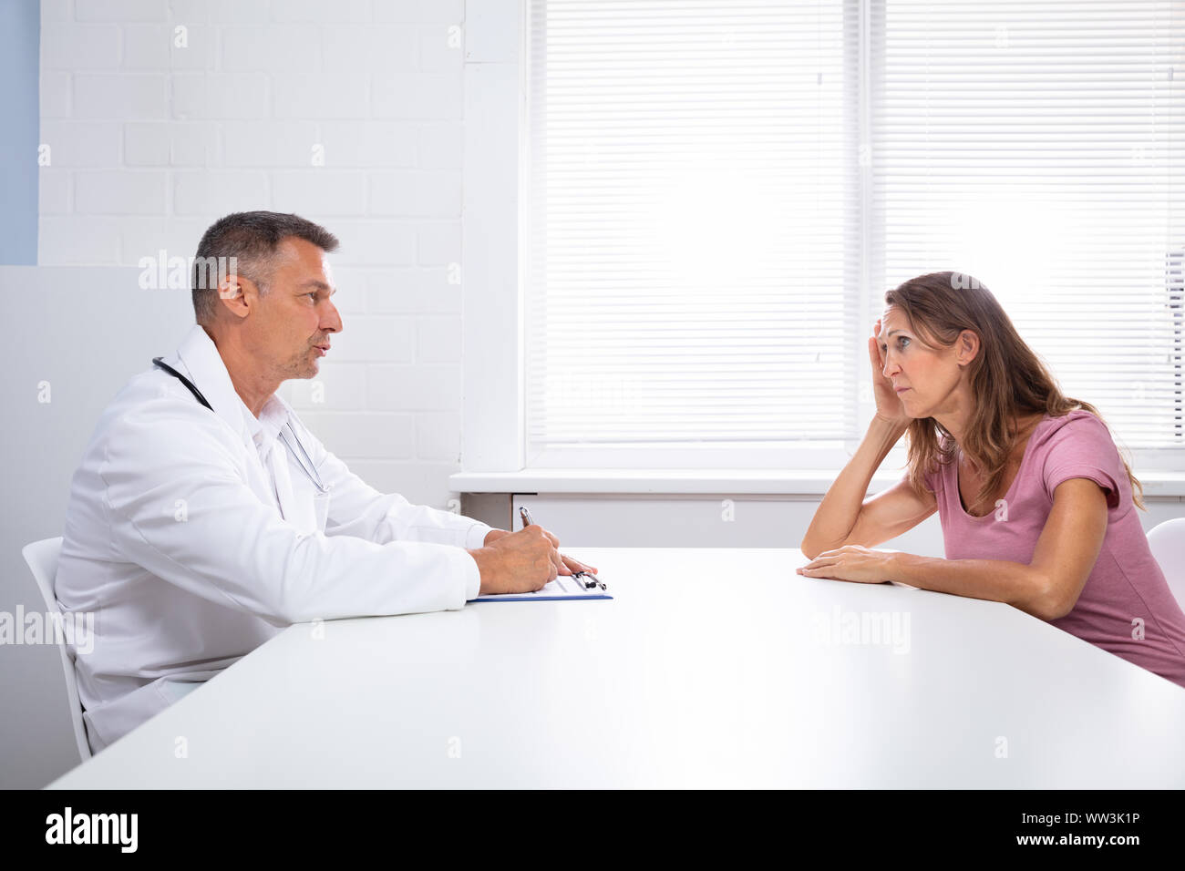 Side View Of Mature Male Doctor Giving Prescription To Female Patient ...
