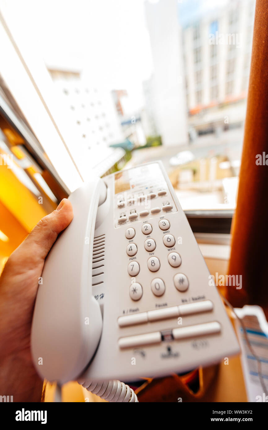 Man hand holding old vintage keypad telephone in hand in hotel room ...