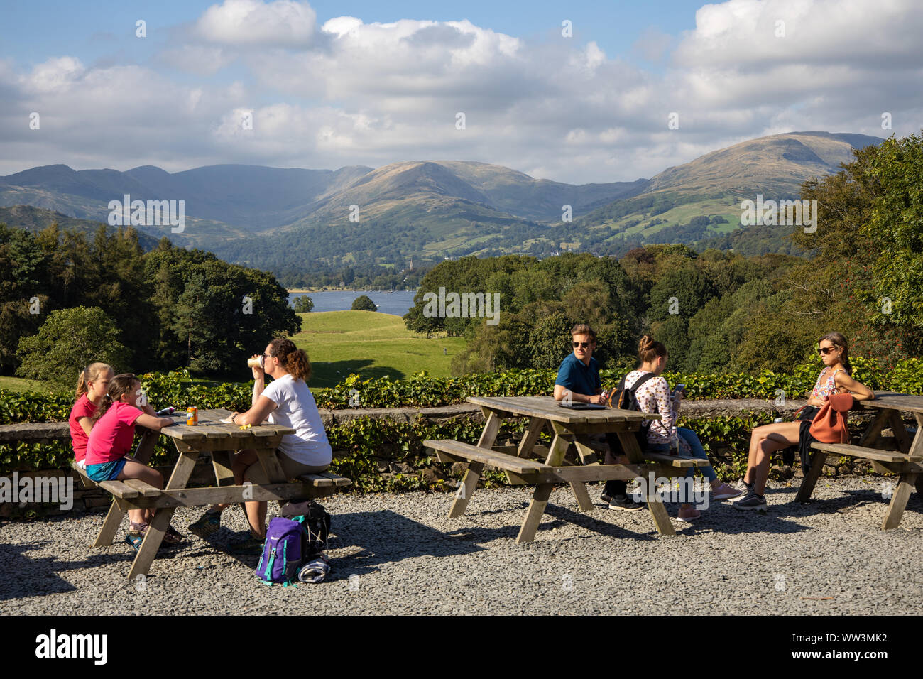People sat at picnic benches enjoying view of Coniston Water Stock ...