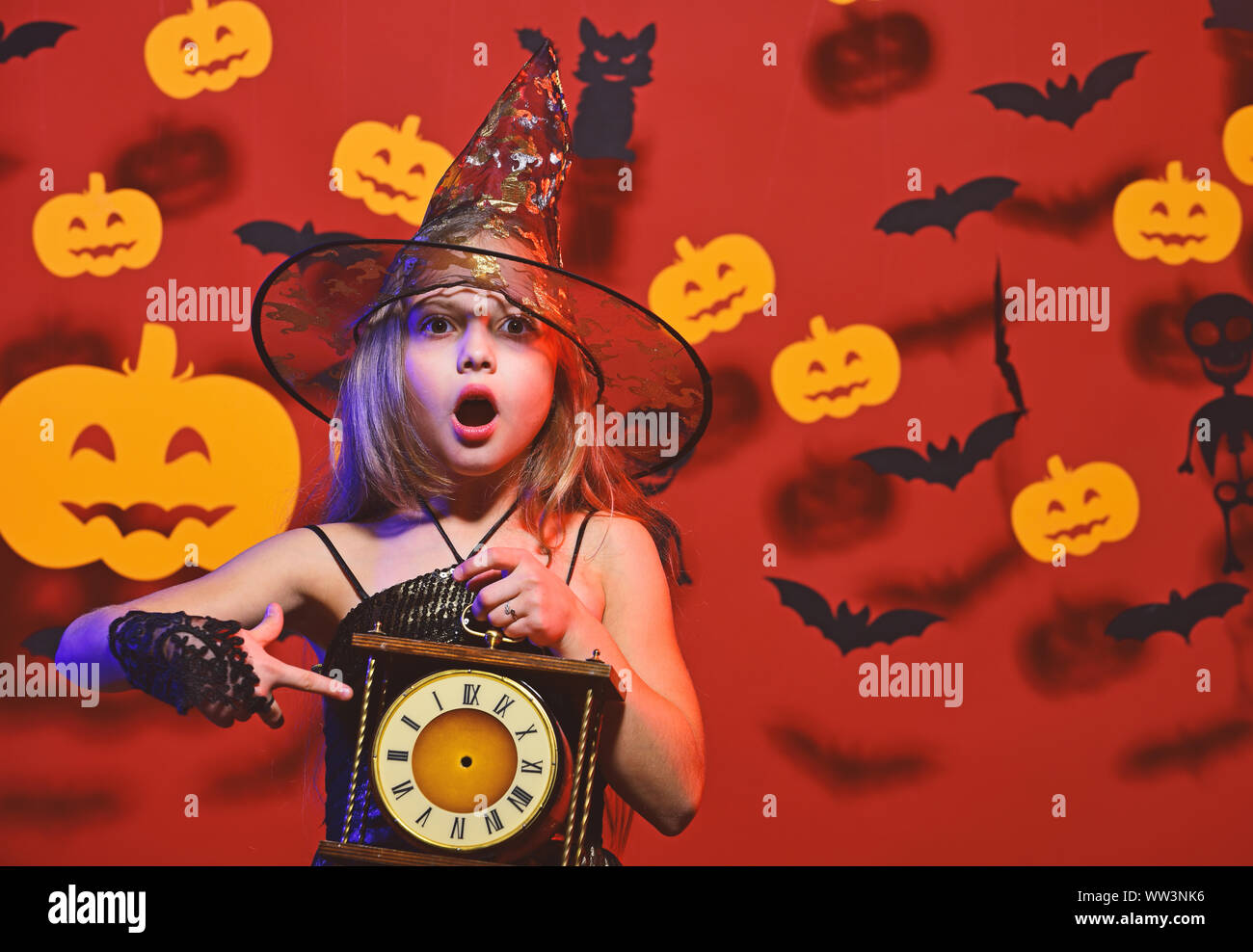 Little witch wearing black hat. Kid in spooky witches costume points at ...