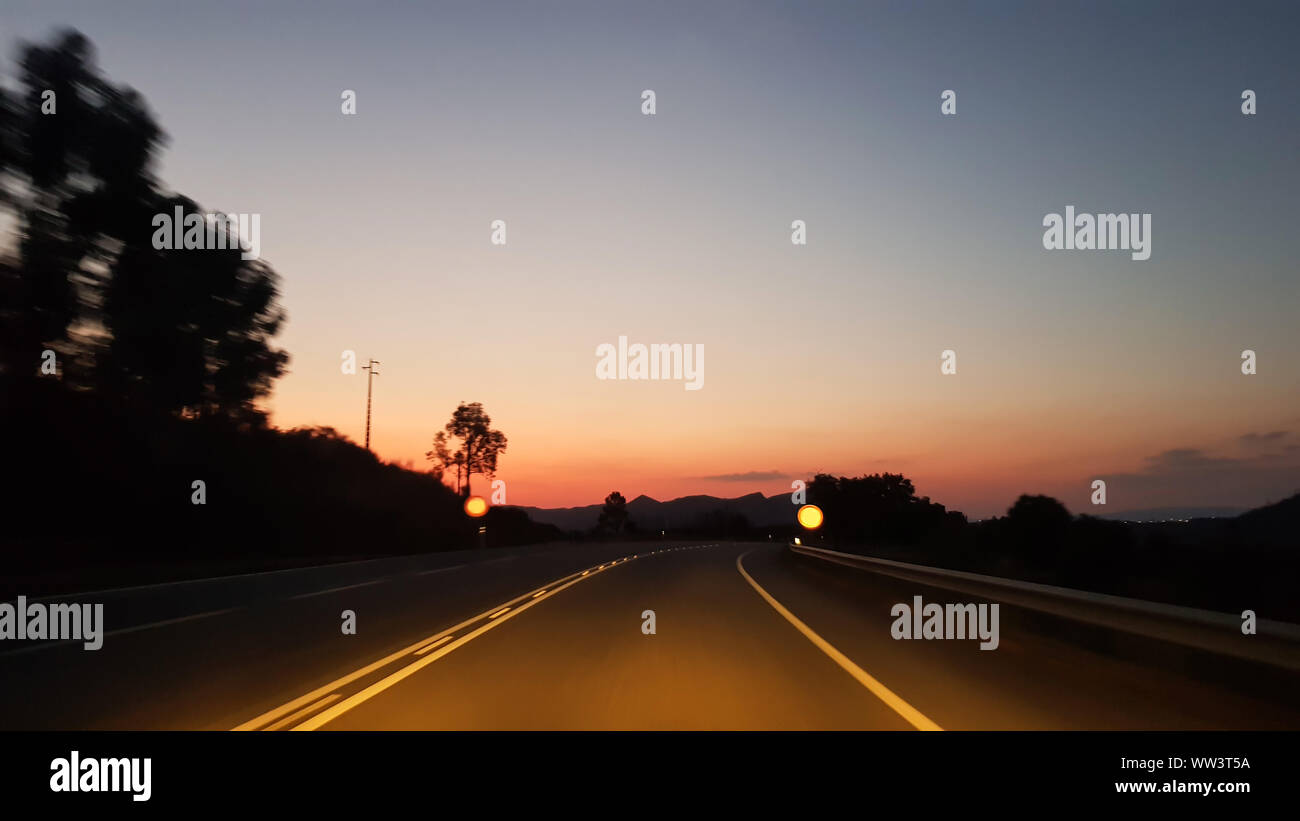 Driving on empty road at sunset Stock Photo - Alamy