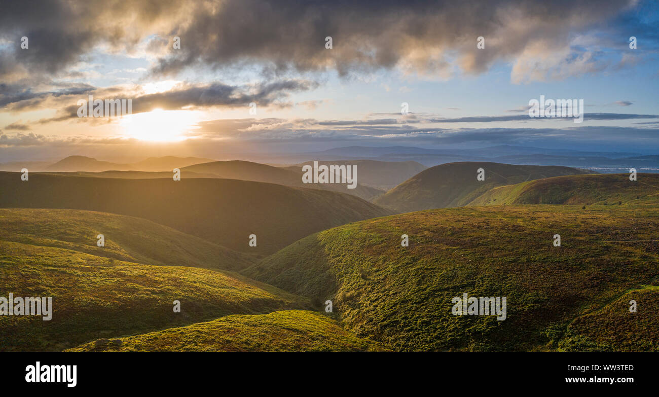 Aerial panoramic view over scenic hills at stormy dramatic sunrise ...