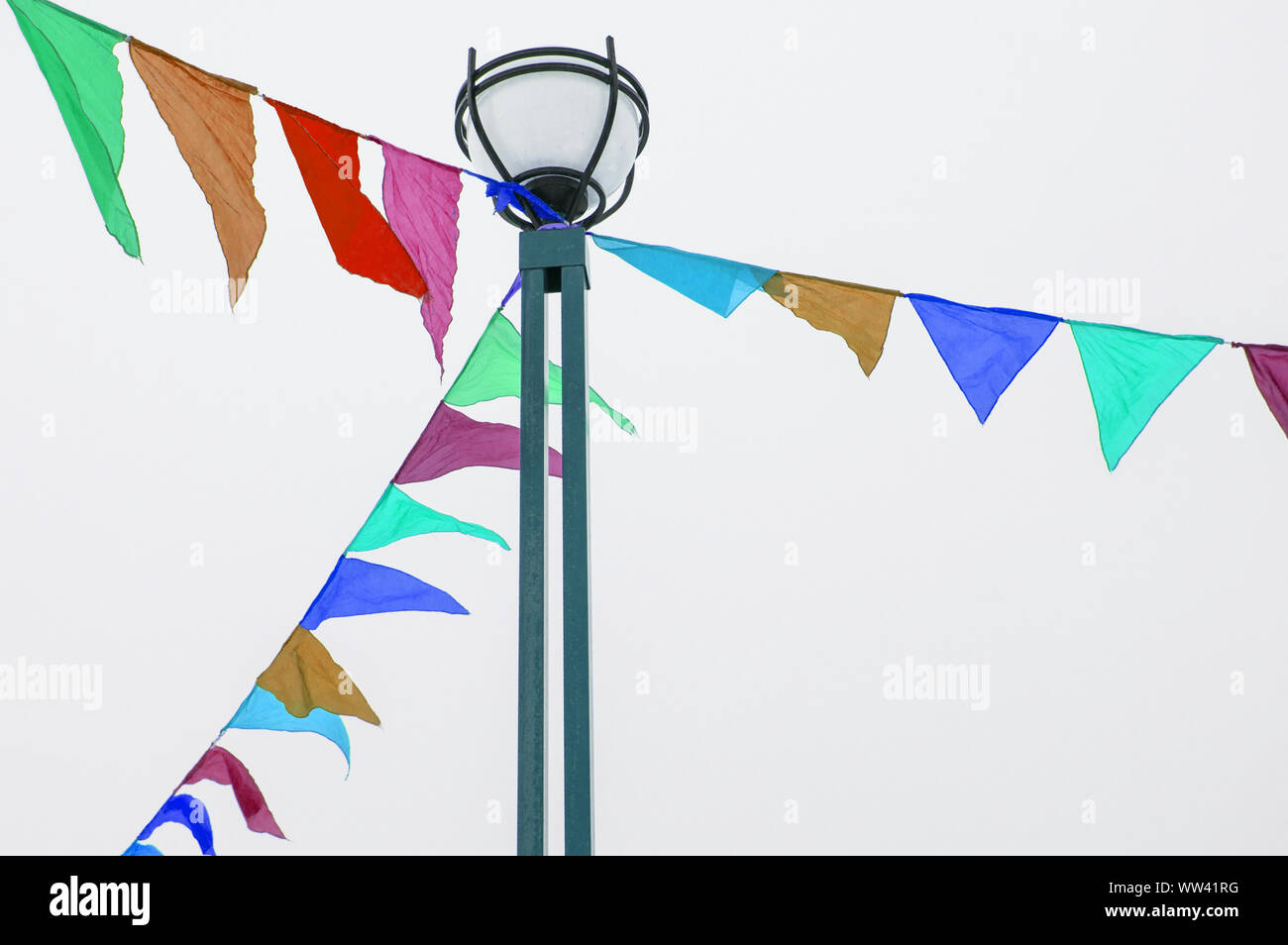 Colorful triangular cloth flags hanging on ropes tied to a lamppost ...