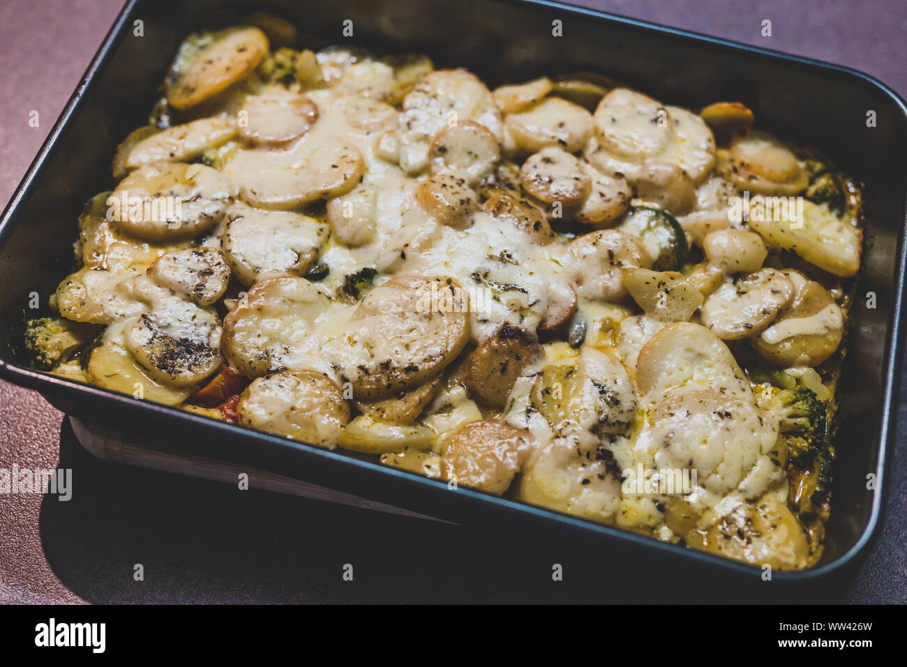 plant-based potato and veggies bake with vegan cheese topping and herbs ...