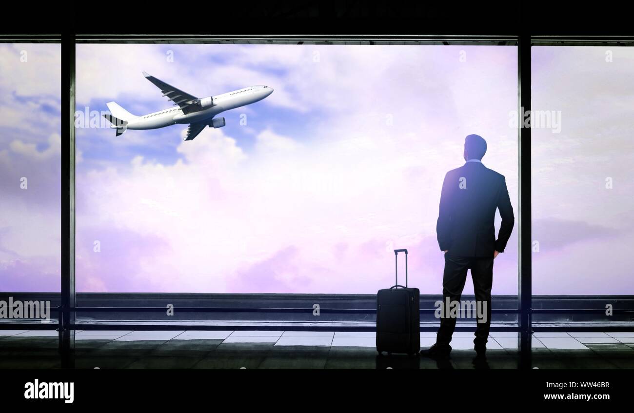 Man standing and looking out at the airport window while waiting for ...