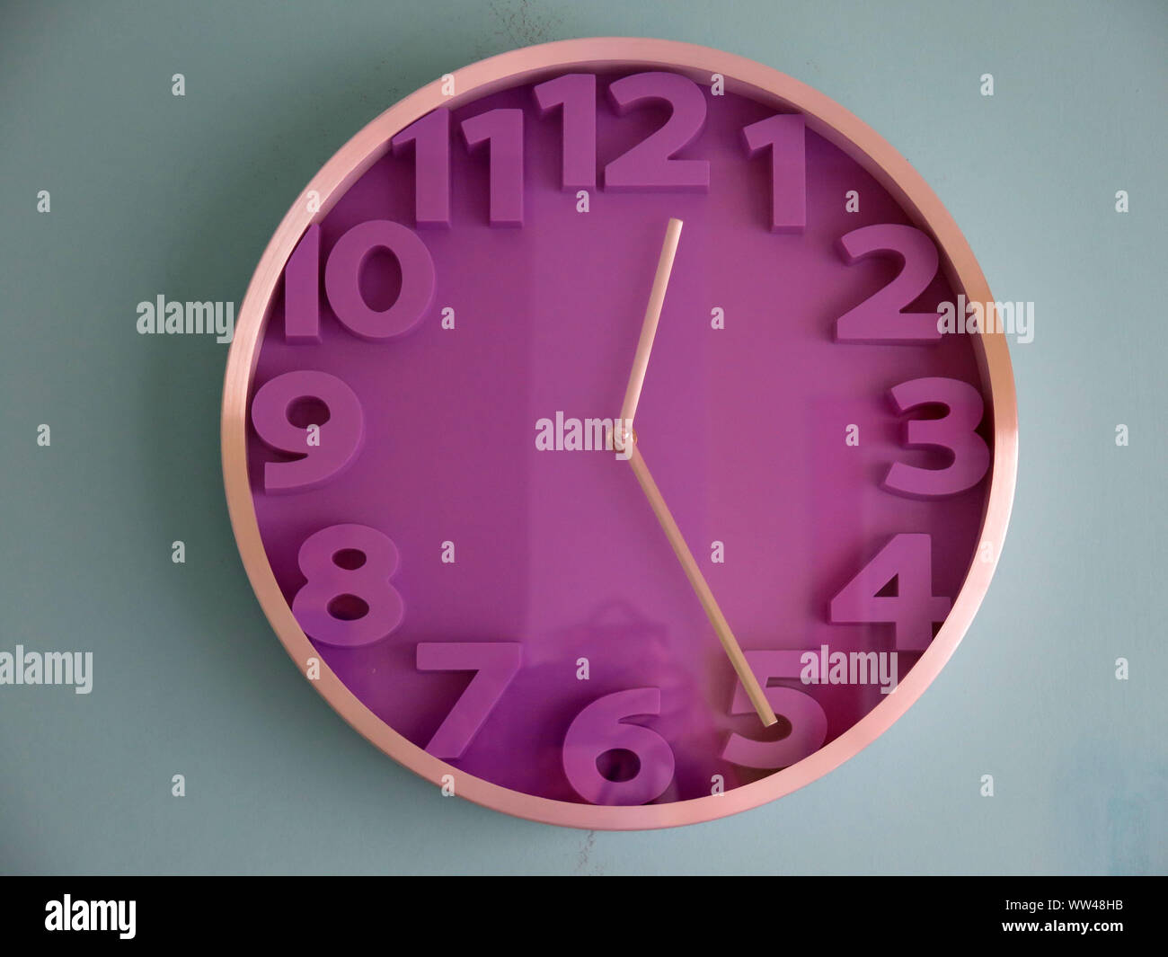 Modern stylish colored wall clock on painted background Stock Photo - Alamy