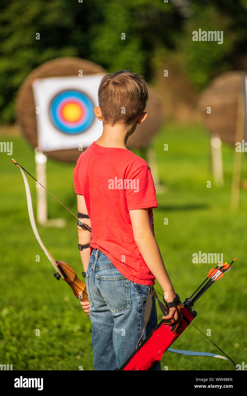Rewar view of a boy standing in front of an archery target before ...