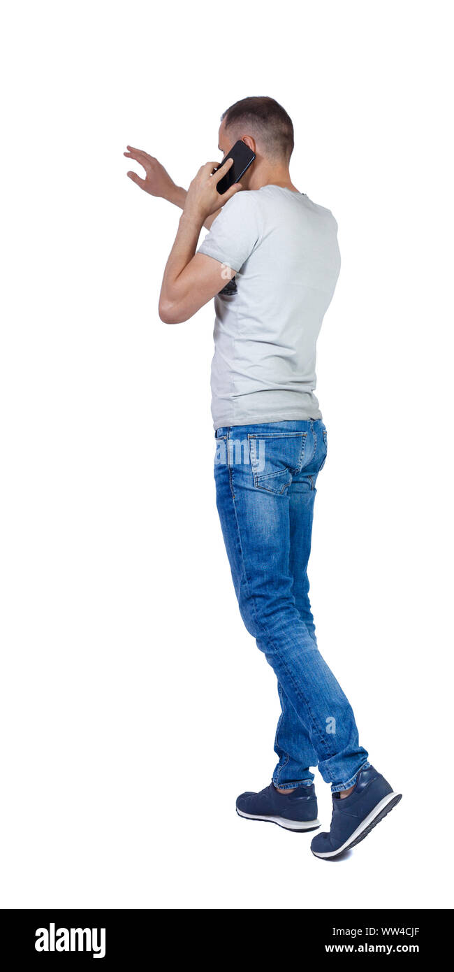 Back view of pointing man in jeans walking with a mobile phone ...