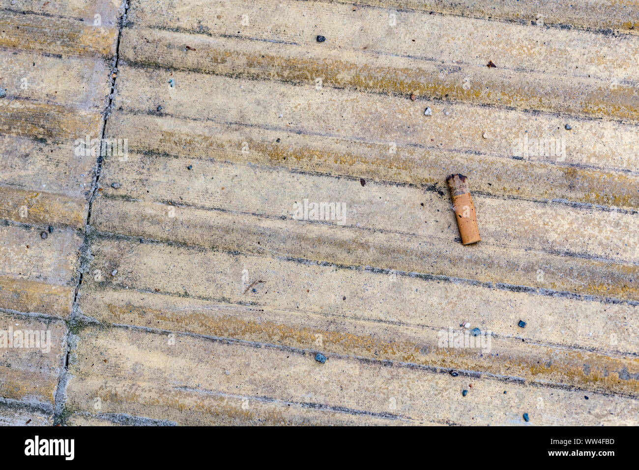 Stubbed out cigarette on exterior station paving (Rothmans brand name ...