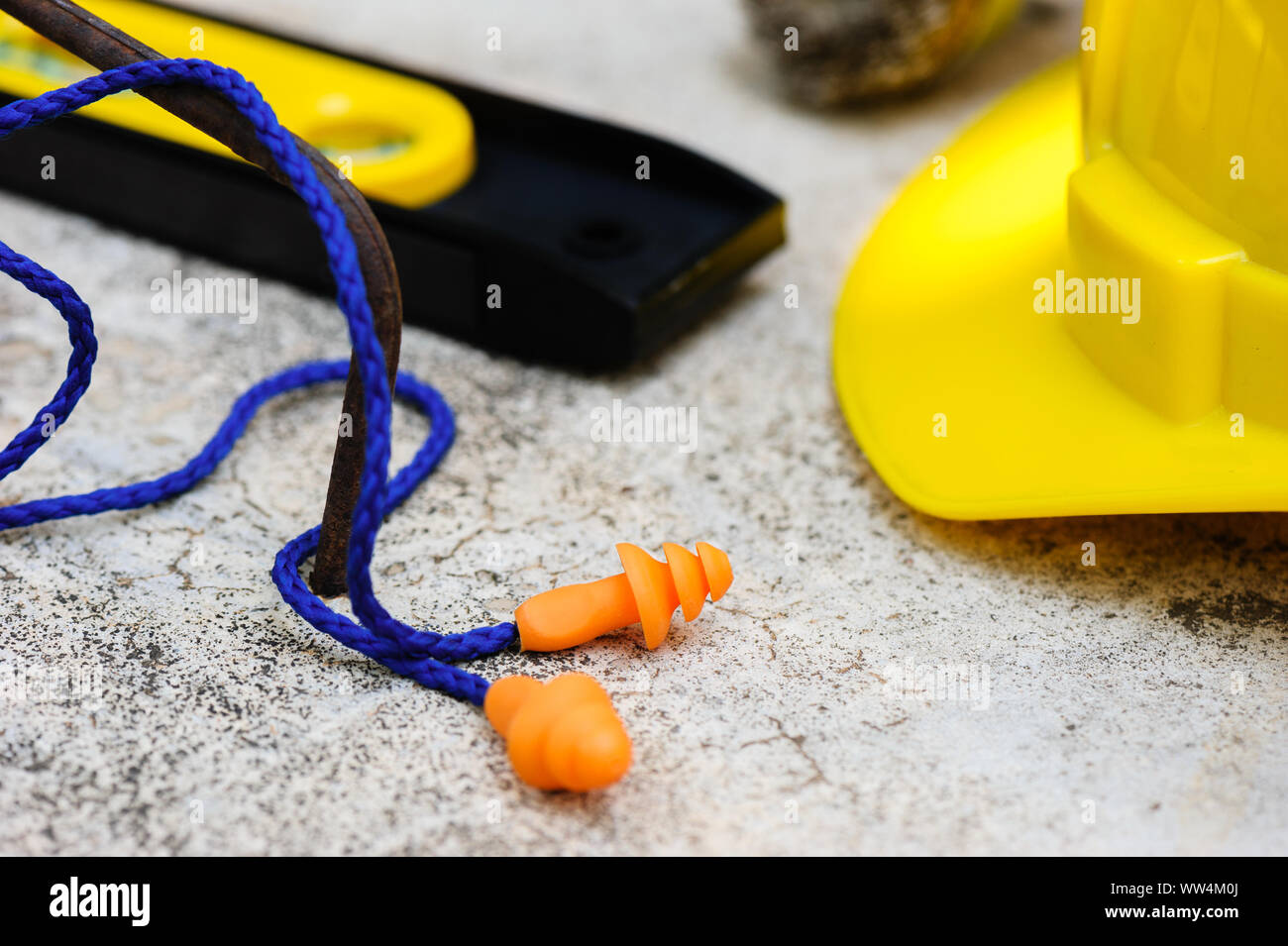 Orange reusable ear plugs in construction site, personal safety ...
