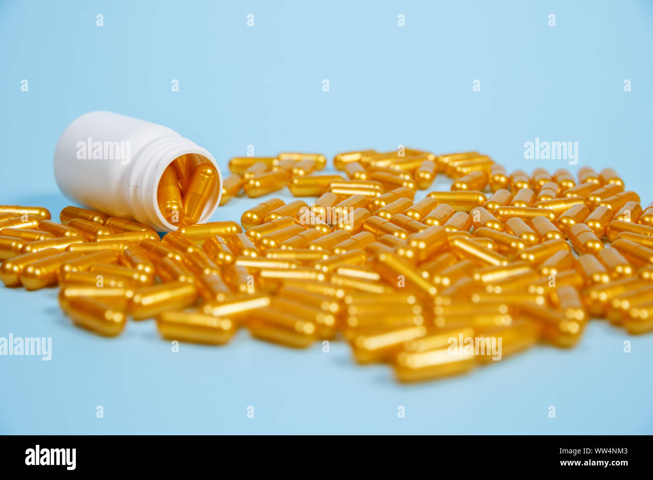 Golden pill capsules on blue background Stock Photo - Alamy