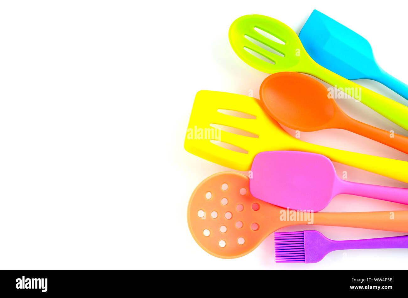 bright multi colored kitchen utensils on white background with copy ...
