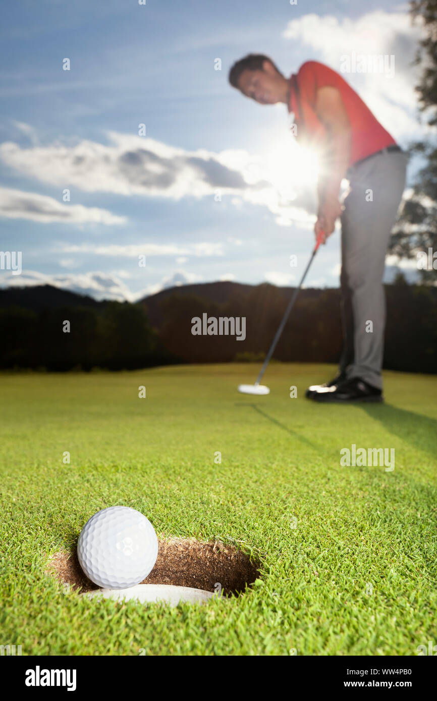 Golfer putting ball into cup Stock Photo - Alamy