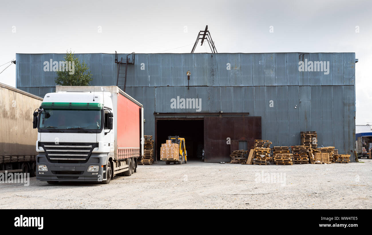 Delivering and supply concept image. Trucks loading at facility in the ...