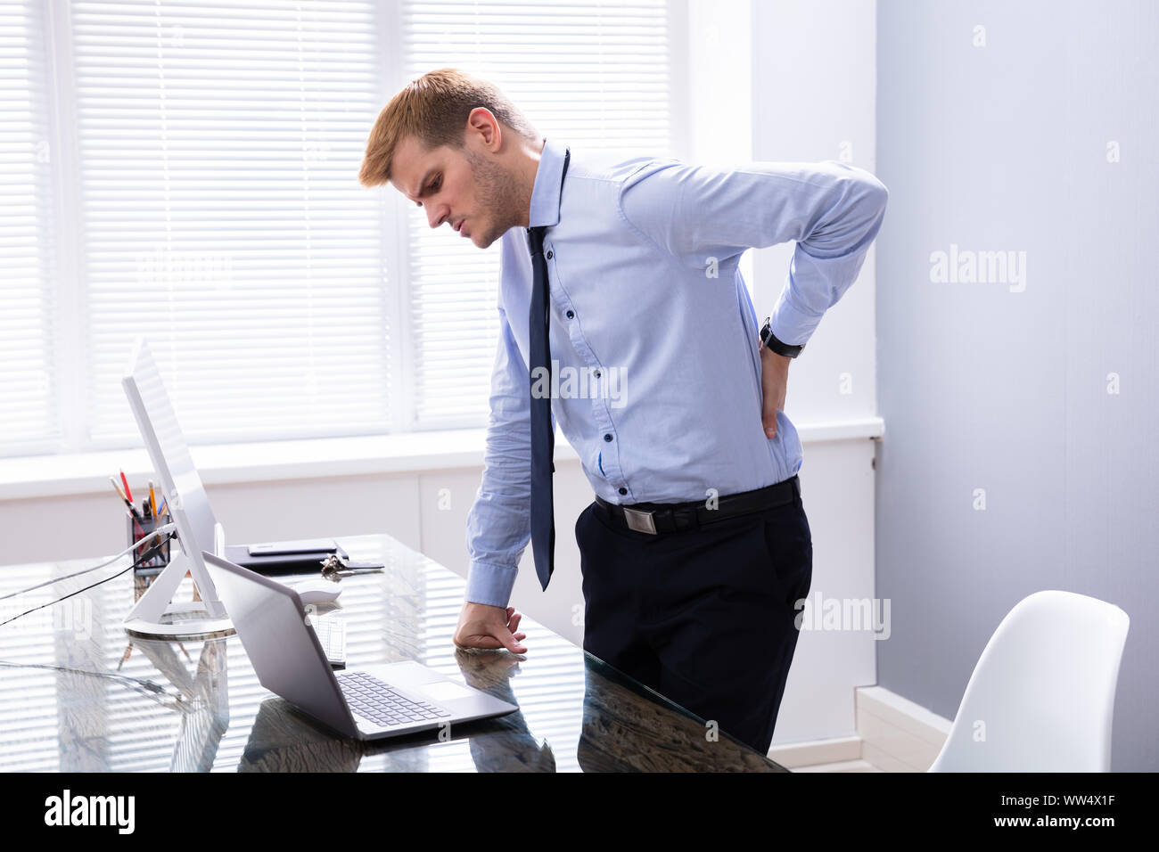 Businessman With Lower Back Ache Standing Near Office Desk Stock Photo ...