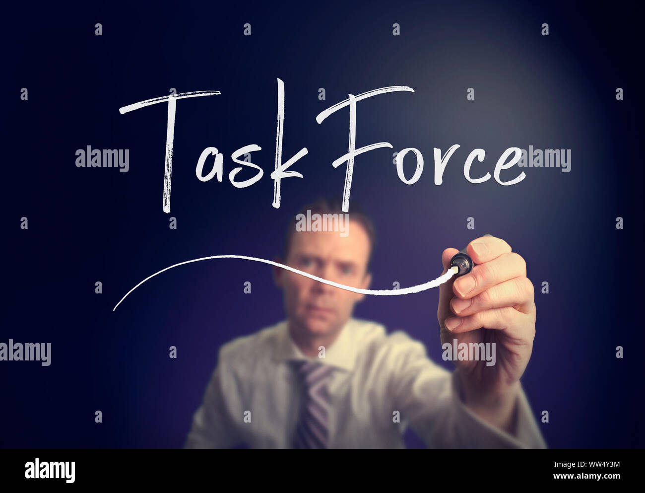 A businessman writing a Task Force concept with a white pen on a clear ...