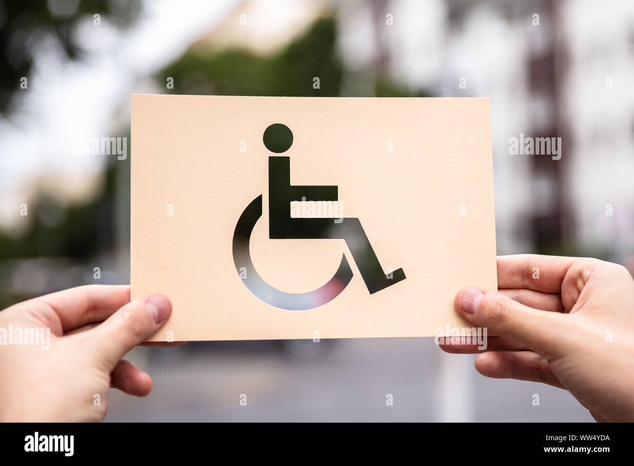 Hands Holding Paper With Cutout Disabled Sign Outdoors Stock Photo - Alamy