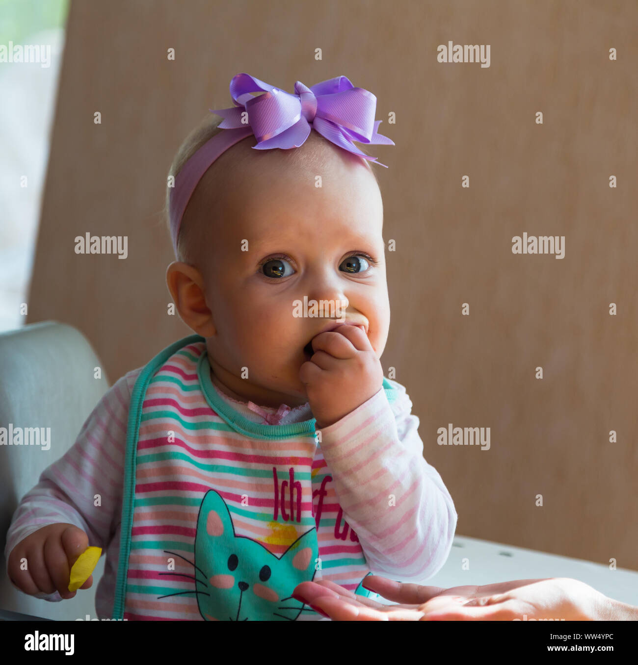 The baby at the table eats his hands Stock Photo - Alamy