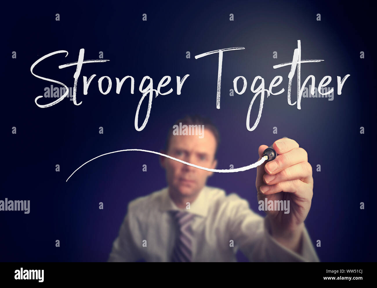 A businessman writing a Stronger Together concept with a white pen on a ...