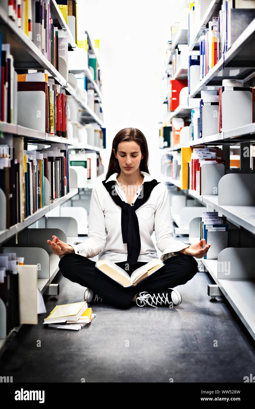 Student meditating over a book in library Stock Photo - Alamy
