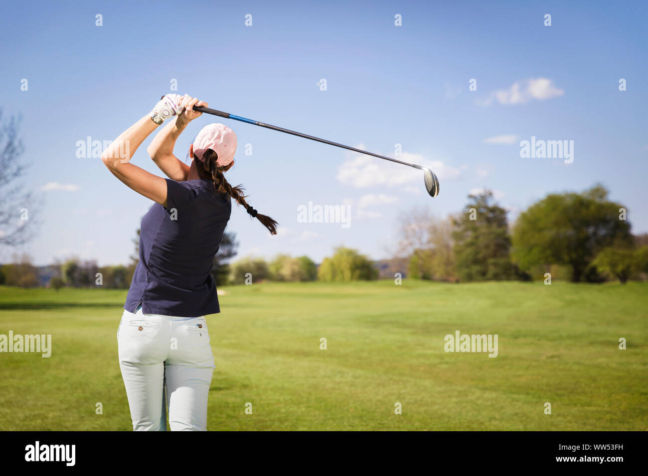 Woman golf player teeing off Stock Photo - Alamy