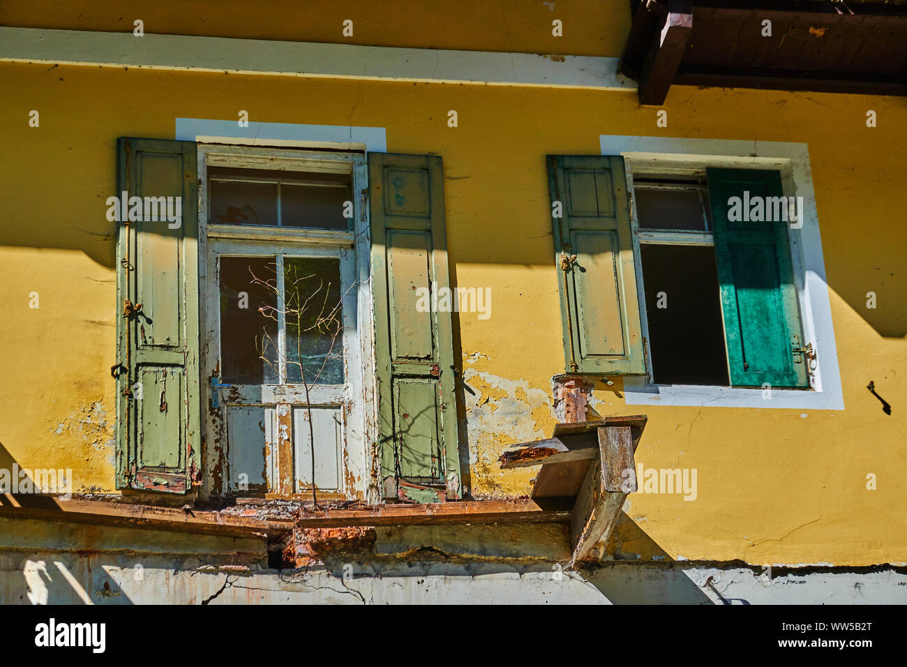 Partial view of a destroyed old house with broken windows and shutters ...