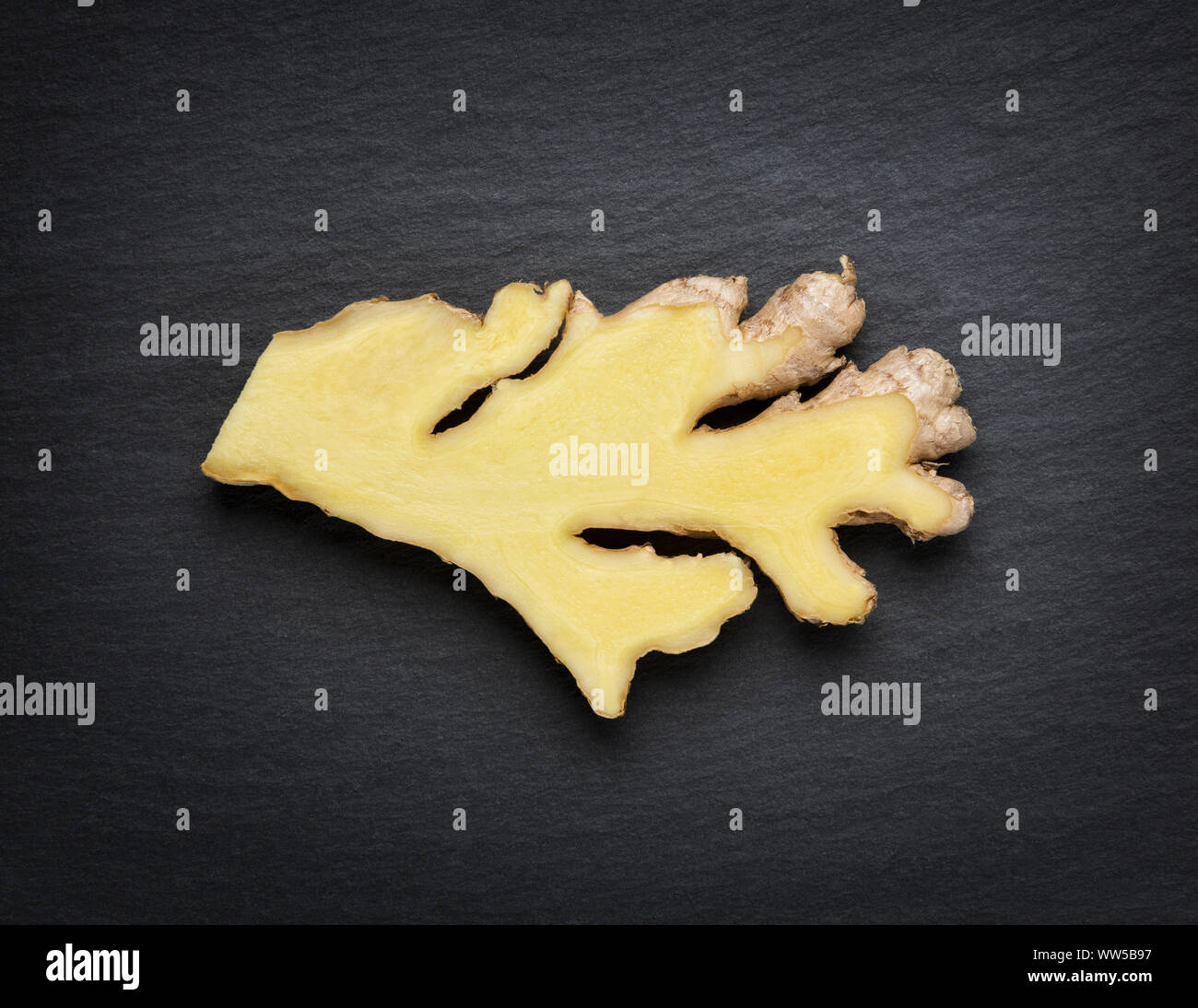 Cut in half ginger isolated on dark stone slab Stock Photo - Alamy