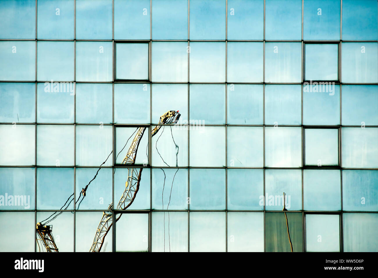 The irregular reflection of a construction crane in a mirror window ...