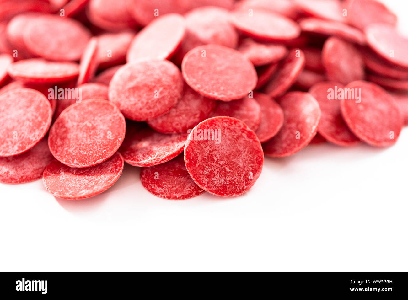 Red round chocolate chips for melting chocolate shapes on a white ...