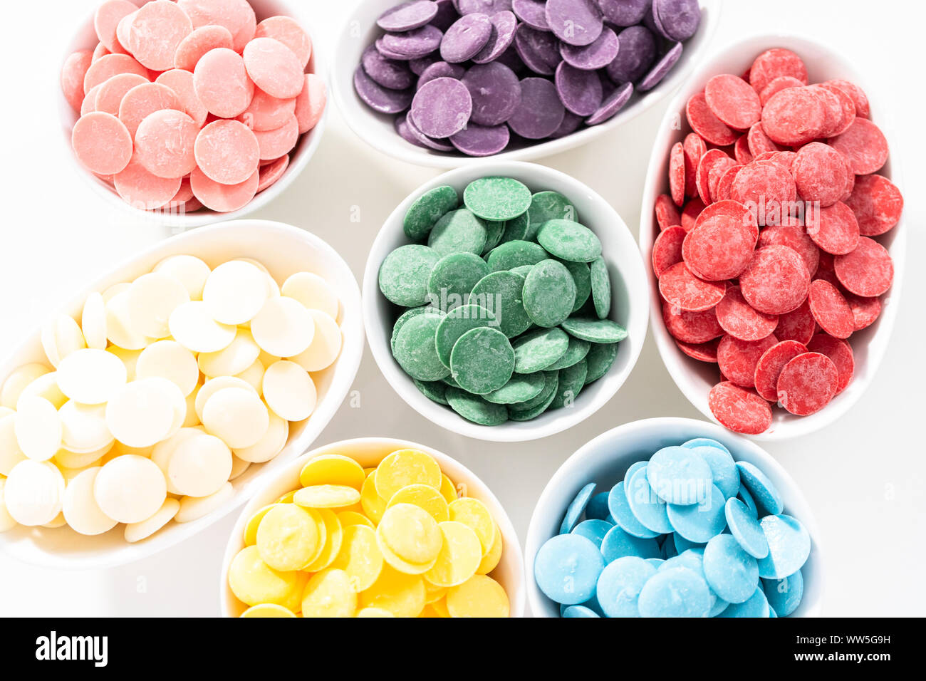 Rainbow colors of round chocolate chips in a white bowls for melting ...