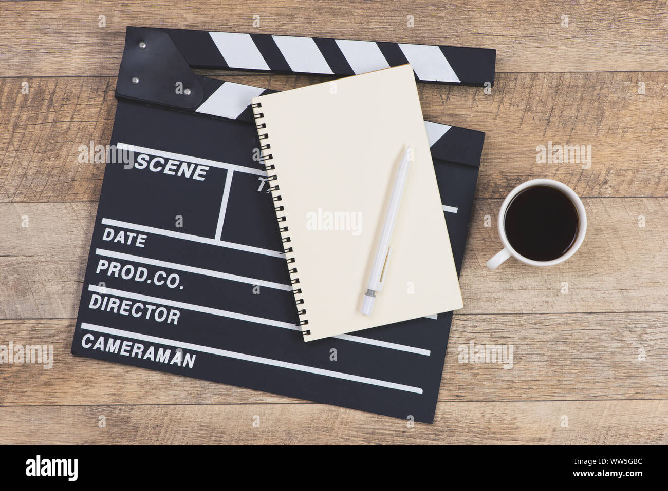 Movie clapper with paper, pen and cup of coffee on wooden planks ...
