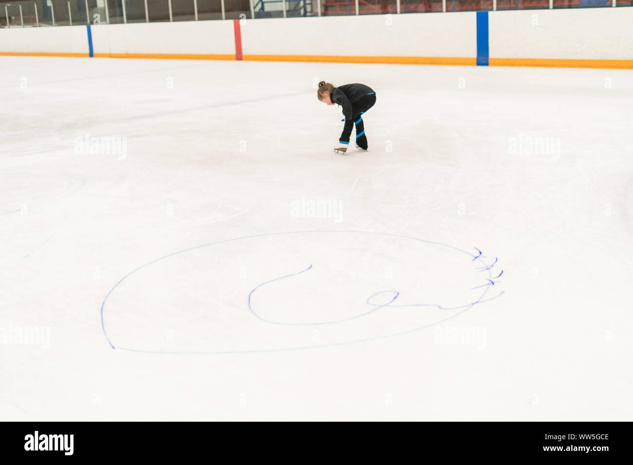 Young figure skater drawing with marker on ice at indoor ice arena ...
