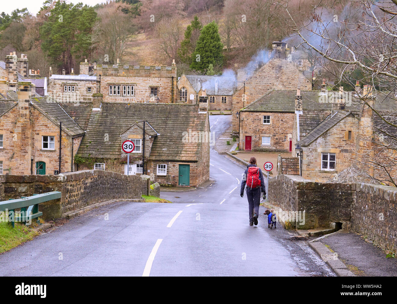 A hiker and their dog out walking through the village of Blanchland ...