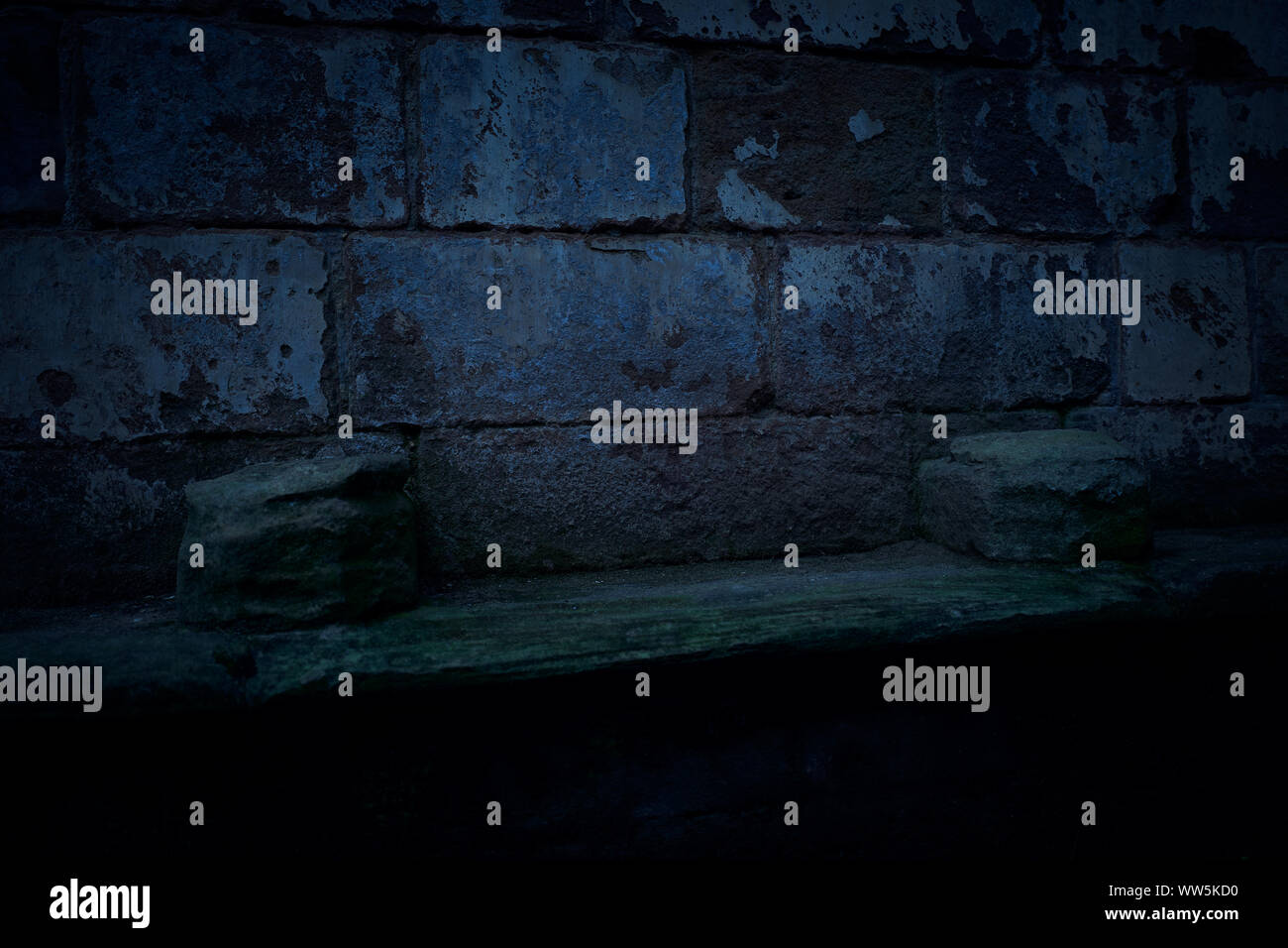 A dark and spooky background of two old and worn plinths on a stone ...