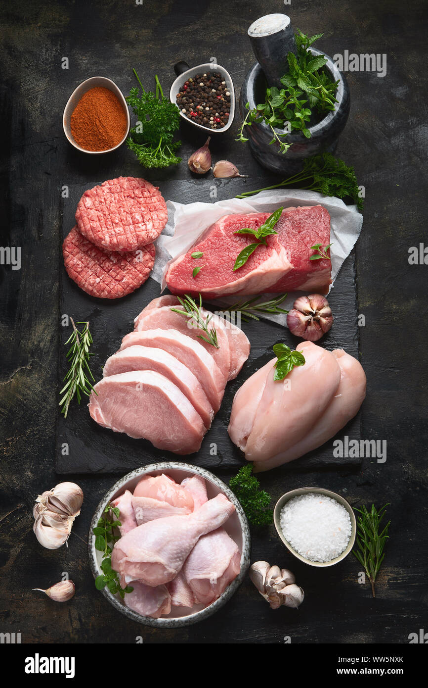 Different types of raw meat on black background. Top view Stock Photo ...
