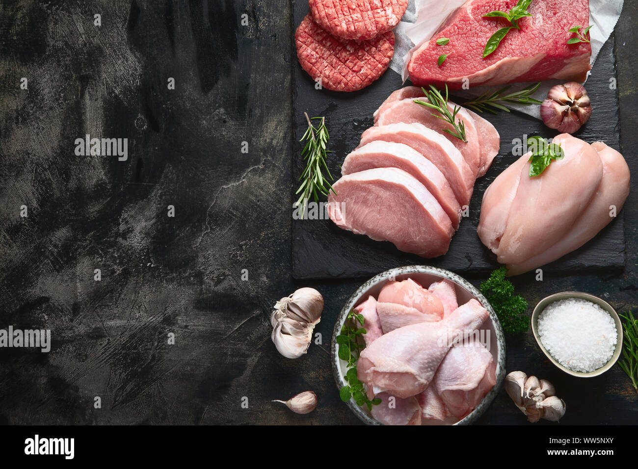Different types of raw meat on black background. Top view with copy ...