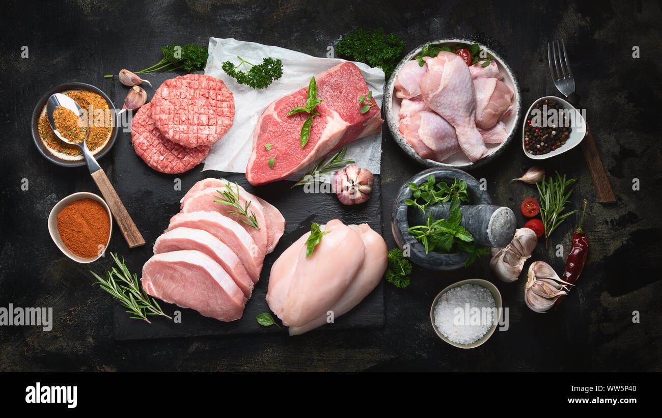 Different types of raw meat on black background. Top view Stock Photo ...