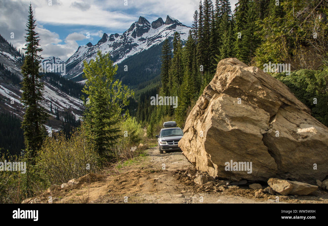 A boulder released by a landslide blocking a dirt mountain road ...