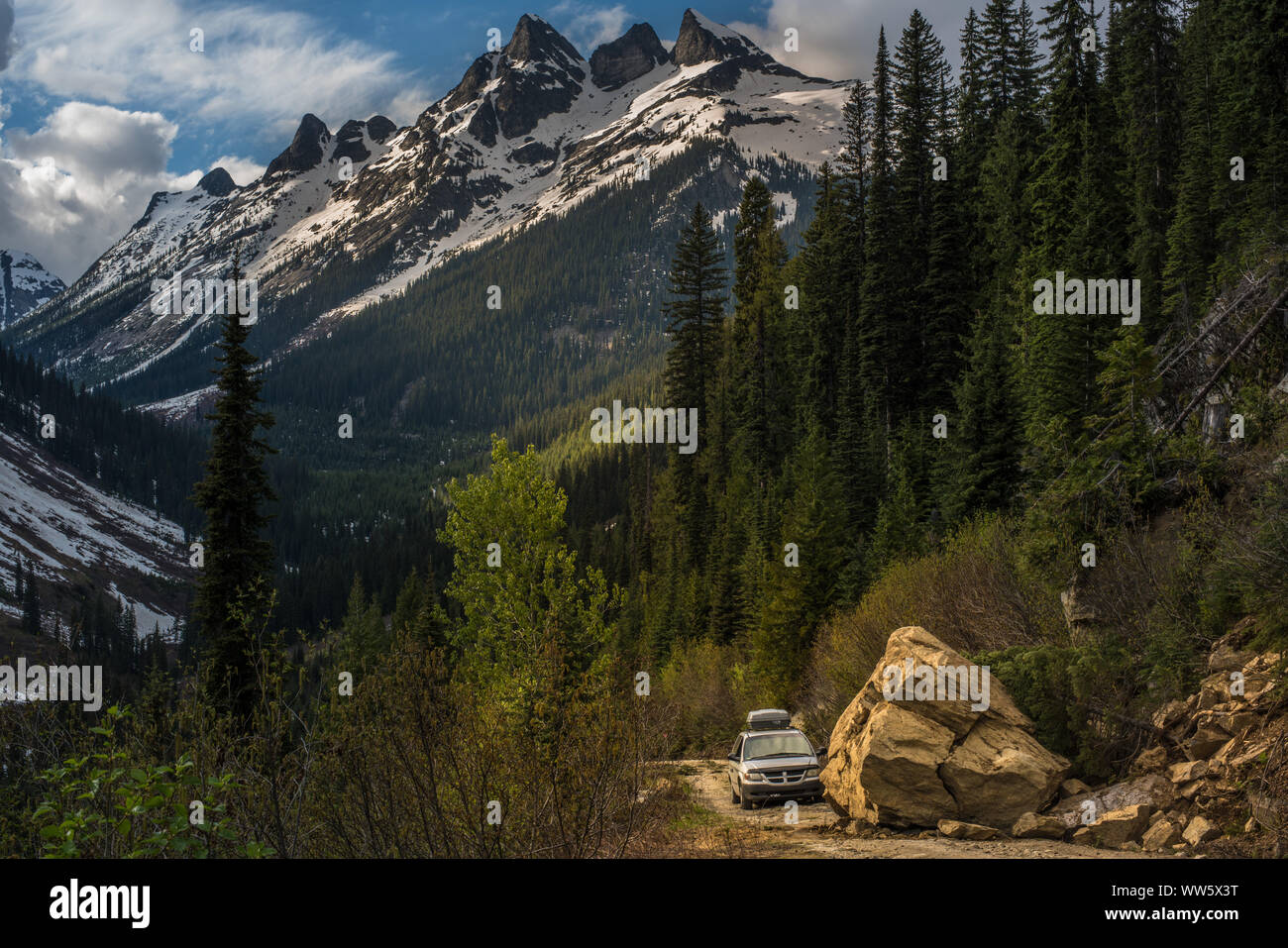 A boulder released by a landslide blocking a dirt mountain road ...