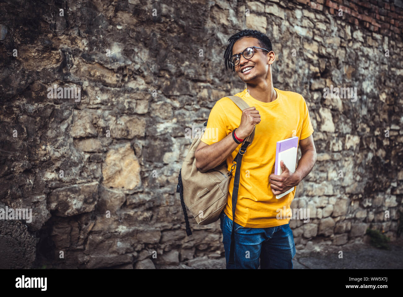Portrait of the young man who is standing outdoor near the old house ...