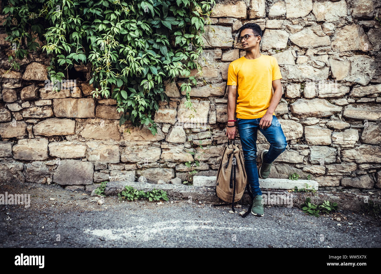Handsome young man standing near the wall and smiling. The concept of ...