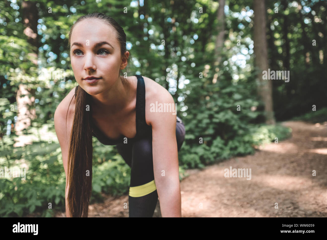 Sporty female preparing to run in the forest. Young athlete woman ...