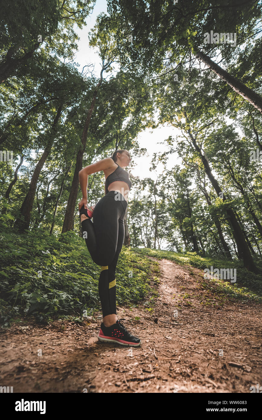 Low angle image of young woman athlete making warm-up before training ...