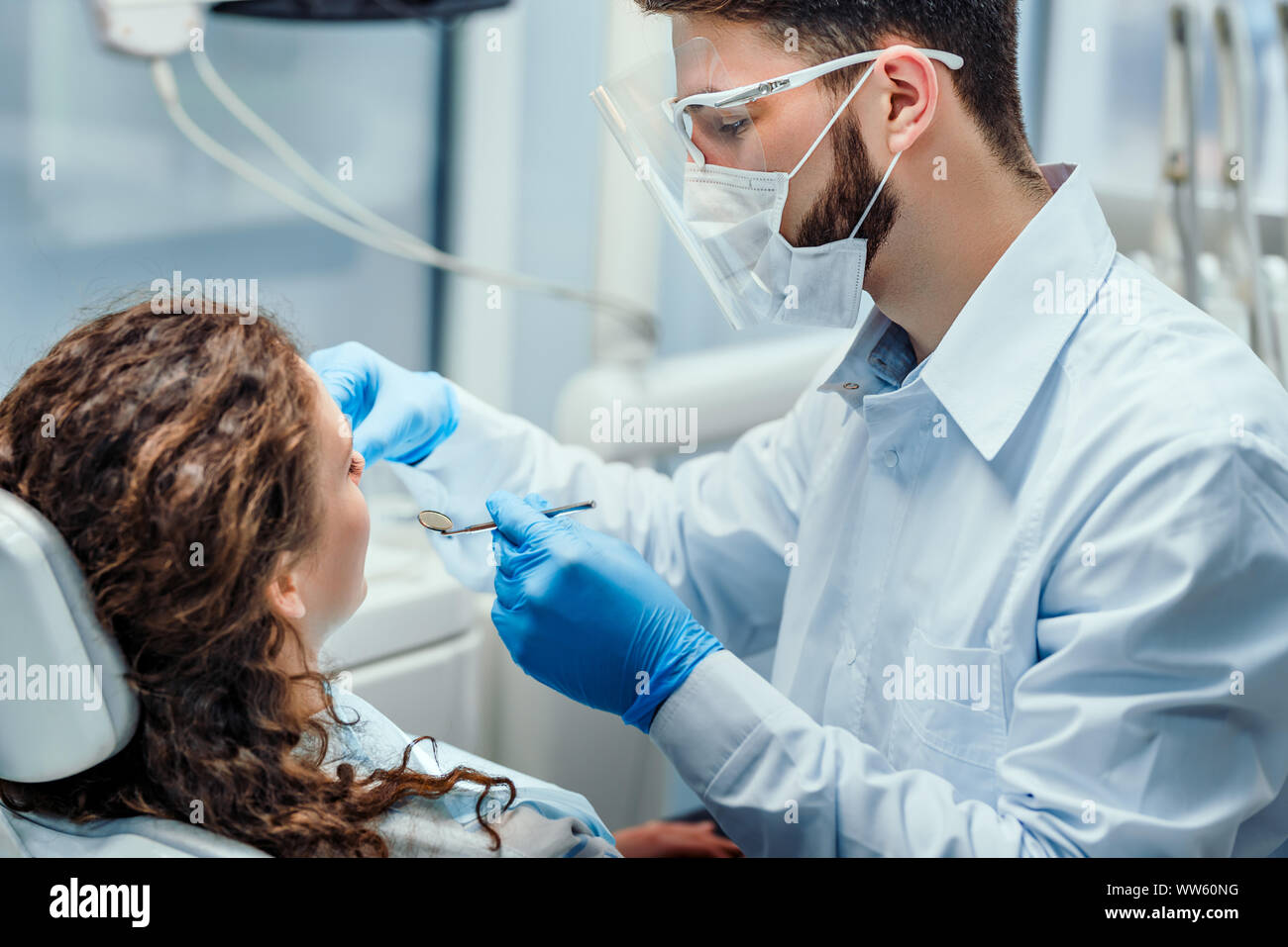 Dentist very carefully check up and repair tooth of his young female ...